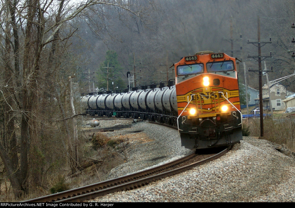 K081 oil empties with BNSF 4443 in charge leans into the curve west of the west end of Reusens.